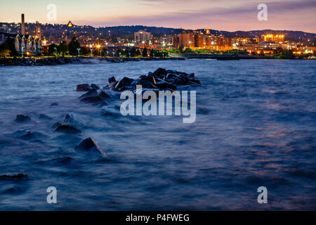 The Duluth, Minnesota skyline illuminated at sunset with crashing waves ...