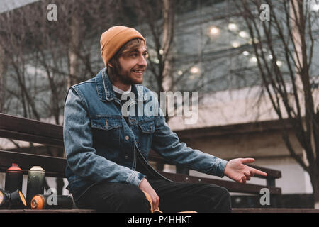 Young caucasian male graffiti artist drawing big street art painting in ...