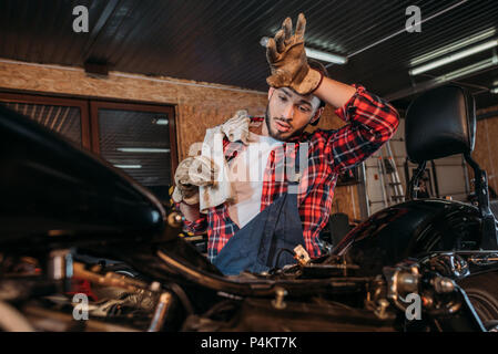 exhausted mechanic wiping sweat after work at garage Stock Photo - Alamy