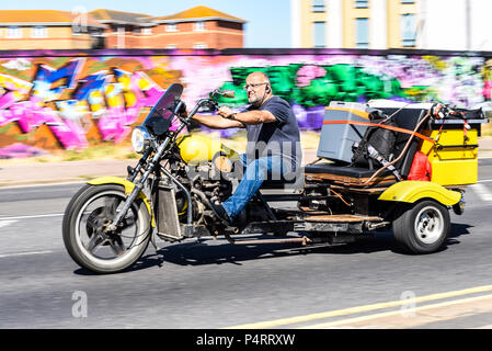 Custom made trike tricycle motorcycle. Passing bright coloured graffiti ...