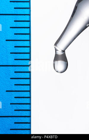 Pipette with blue liquid dripping into water Stock Photo - Alamy