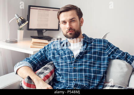 Confident mature bearded man sitting on a chair and looking directly at ...