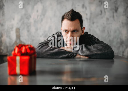 Autistic man sitting against gift in wrapping paper. Alone guy in ...