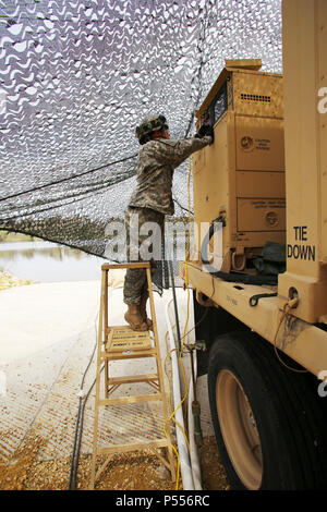 A US Army water purification unit is completing the supply water hookup ...