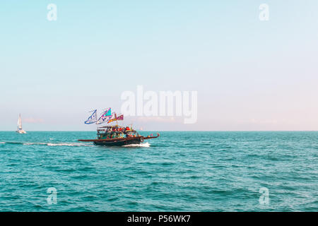 People enjoy traditional boats at sea, while in the background ...