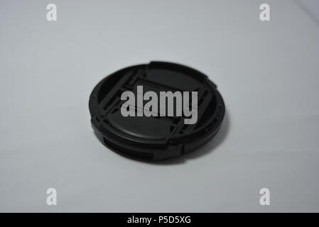 A round black cover from a DSLR camera is located on a white background ...