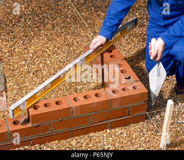 Bricklayer checking level with string line on a house building site ...
