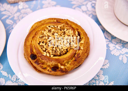Homemade sweet bun with honey almonds on a white wooden background ...