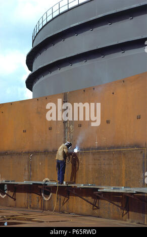 A man welding steel plates on the hull of a new tugboat under ...