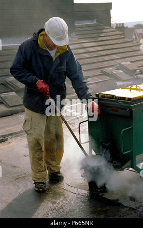 Bituminous Roofing. Pouring Bitumen on a flat roof of a Council Estate ...