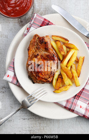 Juicy, browned pork steak on a bone with fried potatoes Stock Photo - Alamy