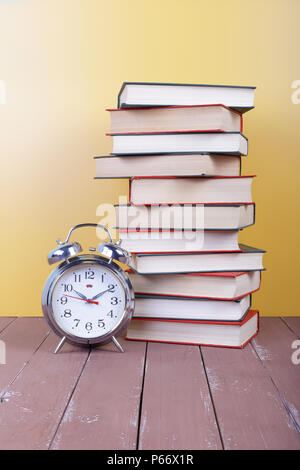 Science and education - alarm clock and high pile group of red books on ...