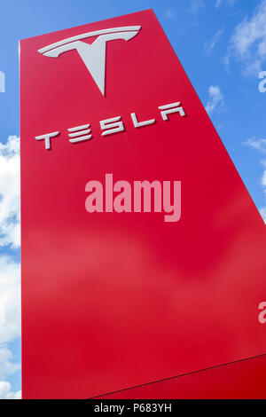 Tesla car brand advertising sign in front of a Tesla car dealership in ...