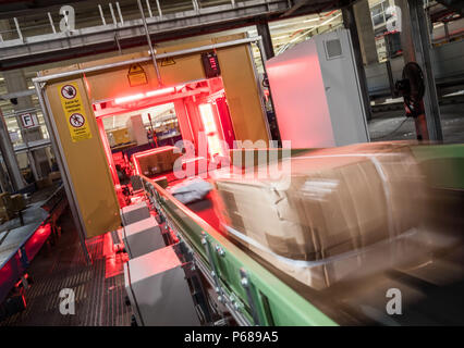 28 June 2018, Germany, Obertshausen: Parcels travel through a scanner ...