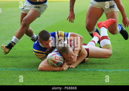 Wigan Warriors Josh Woods goes past Leeds Rhinos Jack Walker to score a ...