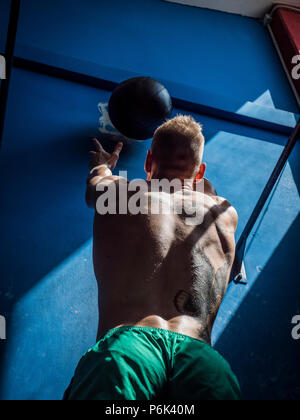 Fit man throwing medicine ball doing ball slam against gym floor or ...