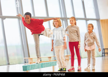 Sporty students balance on a balance beam in physical education Stock ...