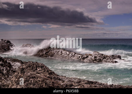Surf hitting the rocks on a beach Stock Photo - Alamy