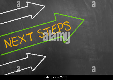 Next steps progress concept with chalk text and direction arrows on ...
