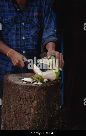 Man cuts young green coconut with a sharp chopper Stock Photo - Alamy