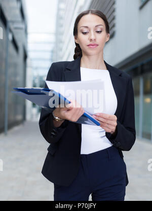 Female creative director is examining documents before signing outdoors ...