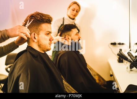 cheerful men clients waiting for their haircuts to be finished at hair ...