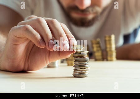Man stacking coins on table, closeup. Savings concept Stock Photo - Alamy