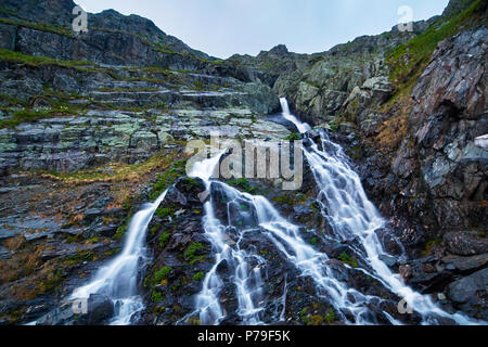 A long exposure shot of a waterfall flowing over rocks in a forest with ...
