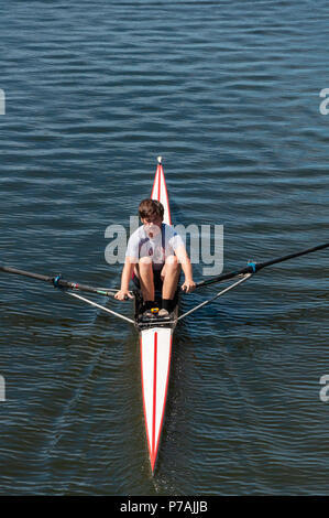 A man sculling in a single scull rowing boat, on the water. Overhead ...