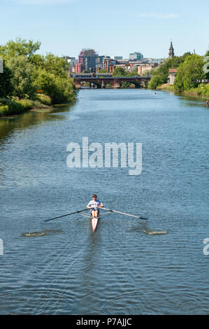 A man sculling in a single scull rowing boat, on the water. Overhead ...