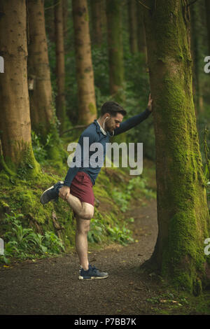 Young fitness man with headphones doing stretching exercises on ...