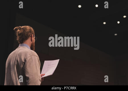 Male actor reading script on stage Stock Photo - Alamy