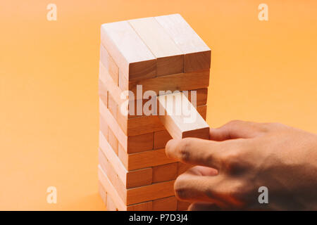 Businessman gambling placing wooden block on a tower Stock Photo - Alamy