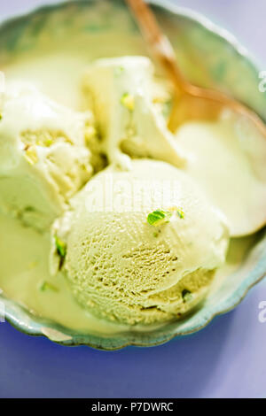 Fresh pistachio ice cream in a bowl with waffle cups. On a wooden table ...