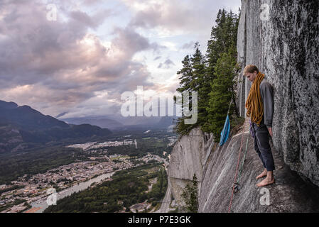 Young man standing on ledge, looking at the Half Dome, view from ...