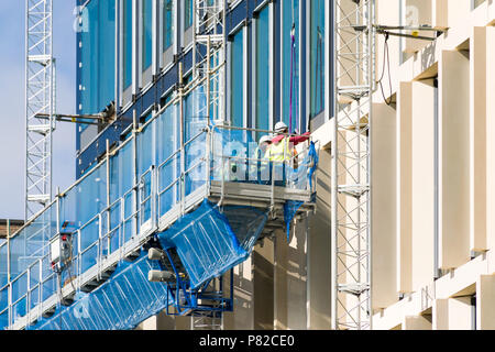 Workmen on a mobile inspection platform inspecting the exterior of a ...