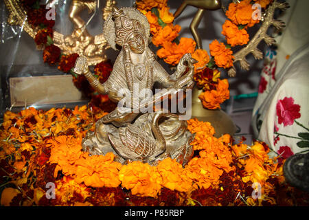 Goddess Saraswati figure. Hindu puja. Incense, offerings, petals ...