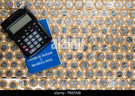 Work permit and black calculator on several Brazilian one real coins ...