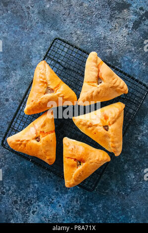 Homemade baked uchpuchmak samsa with meat and potato on a wooden plate ...