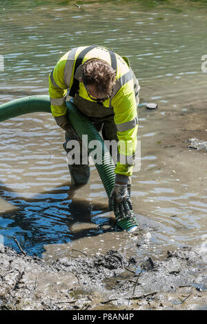 A worker using a suction pump to remove mud and silt in a lake Stock ...