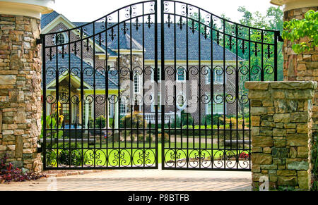 Large brick house behind iron gate Stock Photo - Alamy