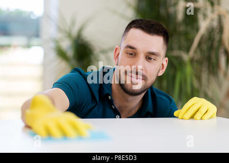 Man cleaning a table with a rag and rubber gloves at home Stock Photo ...