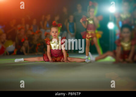 Little girl gymnast sitting on split with green ball Stock Photo - Alamy