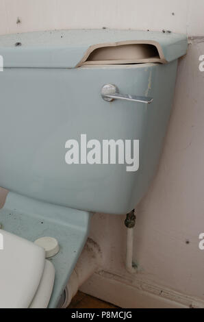 Dirty and dusty bathroom with a toilet which has a broken lid for it's ...
