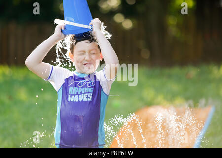 Caucasian boy dumping bucket of water on girls in backyard Stock Photo ...