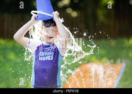 Caucasian boy dumping bucket of water on girls in backyard Stock Photo ...