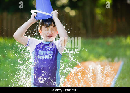 Caucasian boy dumping bucket of water on girls in backyard Stock Photo ...