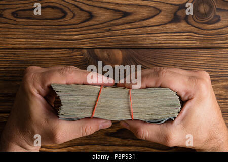 Man gripping a thick stack of 100 dollar bills or Benjamins in his hand ...