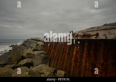 A gloomy day outdoors at a beach with a big bridge under the cloudy sky ...