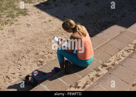 Female athlete using mobile phone while standing on exercise mat Stock ...